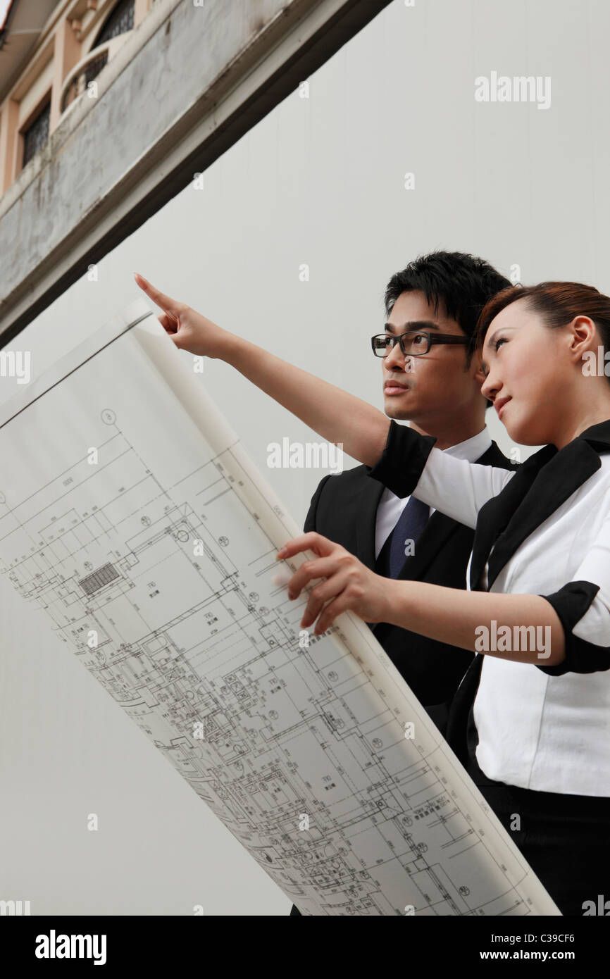 Two people looking at building plans Stock Photo - Alamy