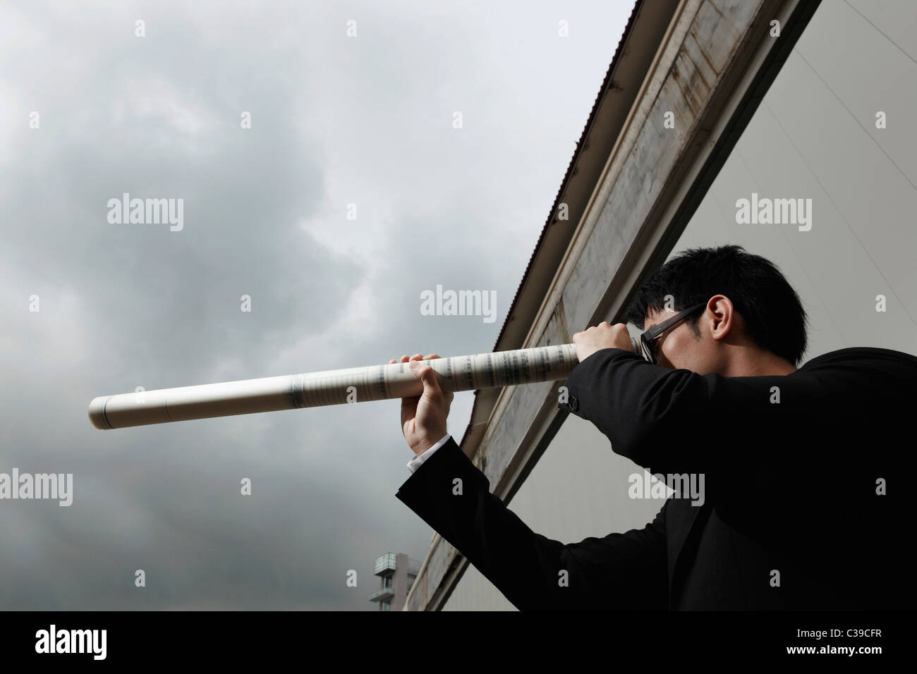 Man looking through building plans like a telescope Stock Photo - Alamy