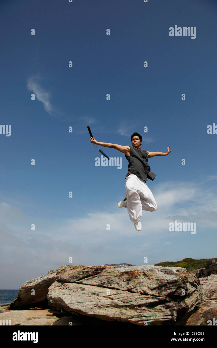 Chinese man jumping in air holding nunchucks Stock Photo - Alamy