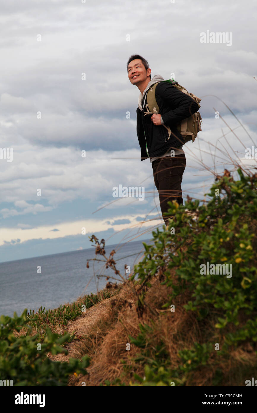 Man wearing back pack and standing on trail over looking ocean Stock ...