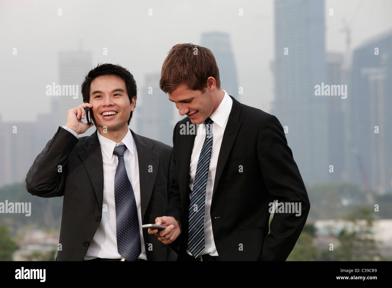 Chinese man talking on phone while Caucasian man texts Stock Photo - Alamy
