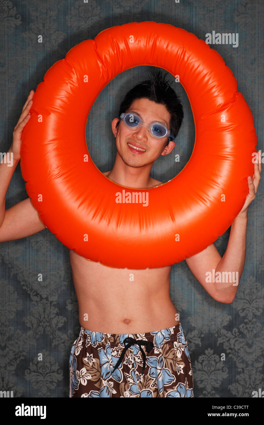 Chinese man looking through orange inner tube and smiling Stock Photo ...