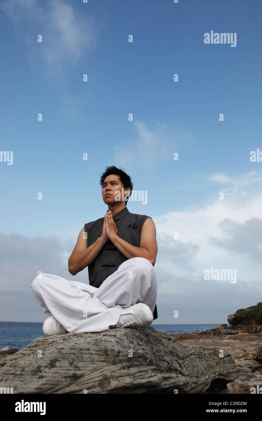 Chinese man doing yoga on rock Stock Photo - Alamy