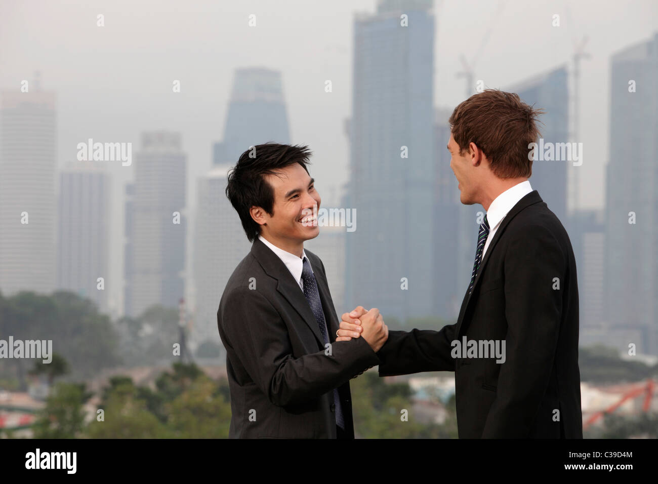 Chinese and Caucasian man shaking hands in front of city sky line Stock ...