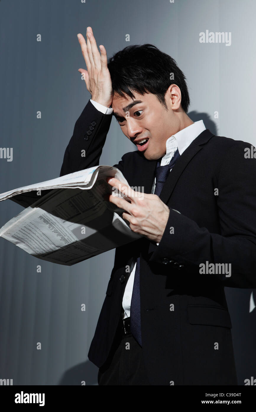 Chinese man holding newspaper hitting his head in surprise Stock Photo ...