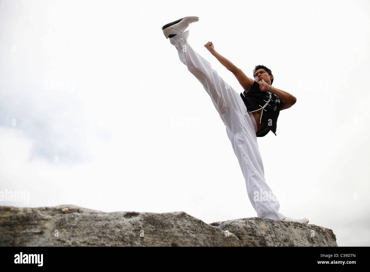 Chinese man doing a high kick on top of rock Stock Photo - Alamy