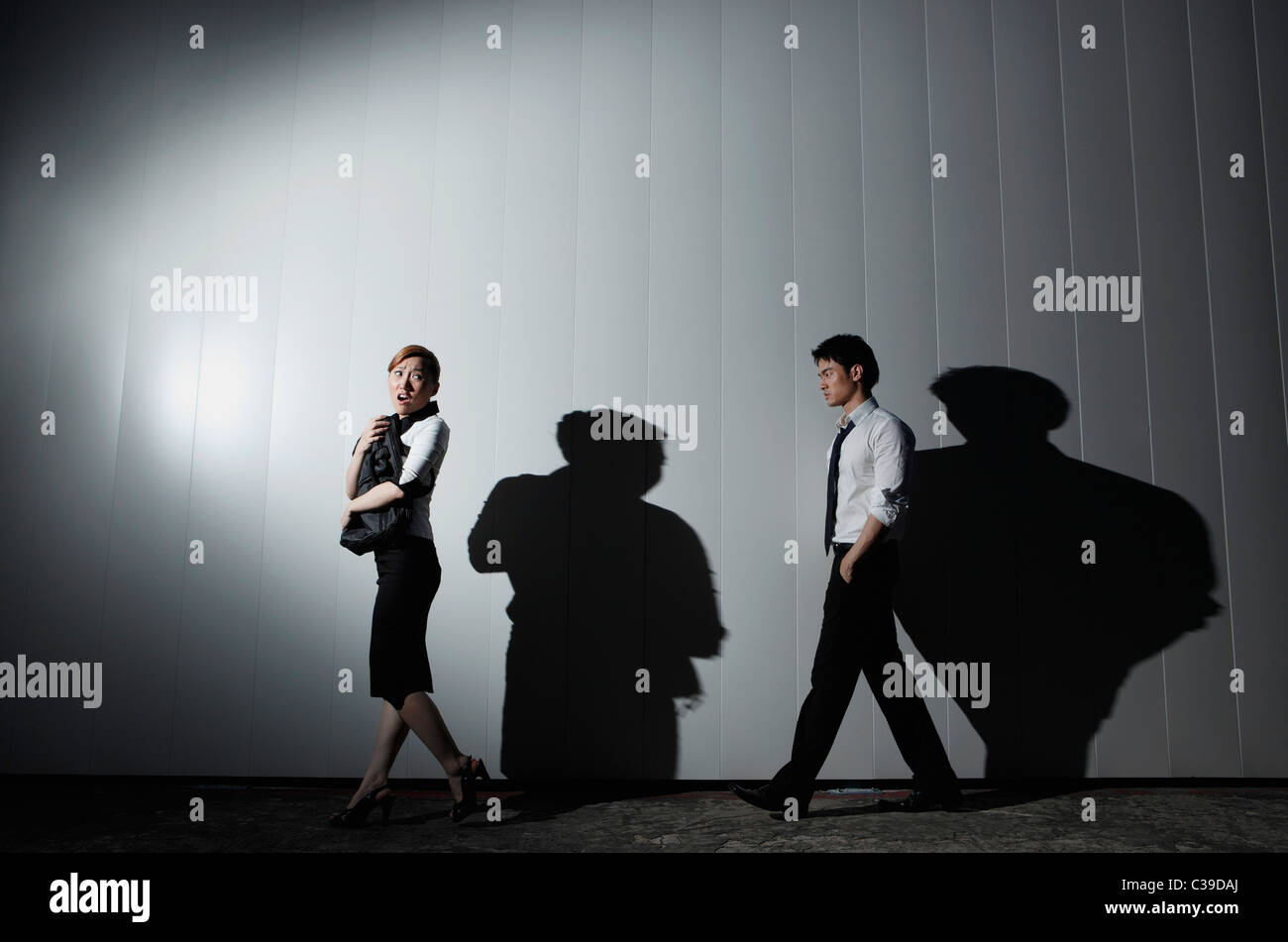A man is following a woman down a street at night Stock Photo - Alamy