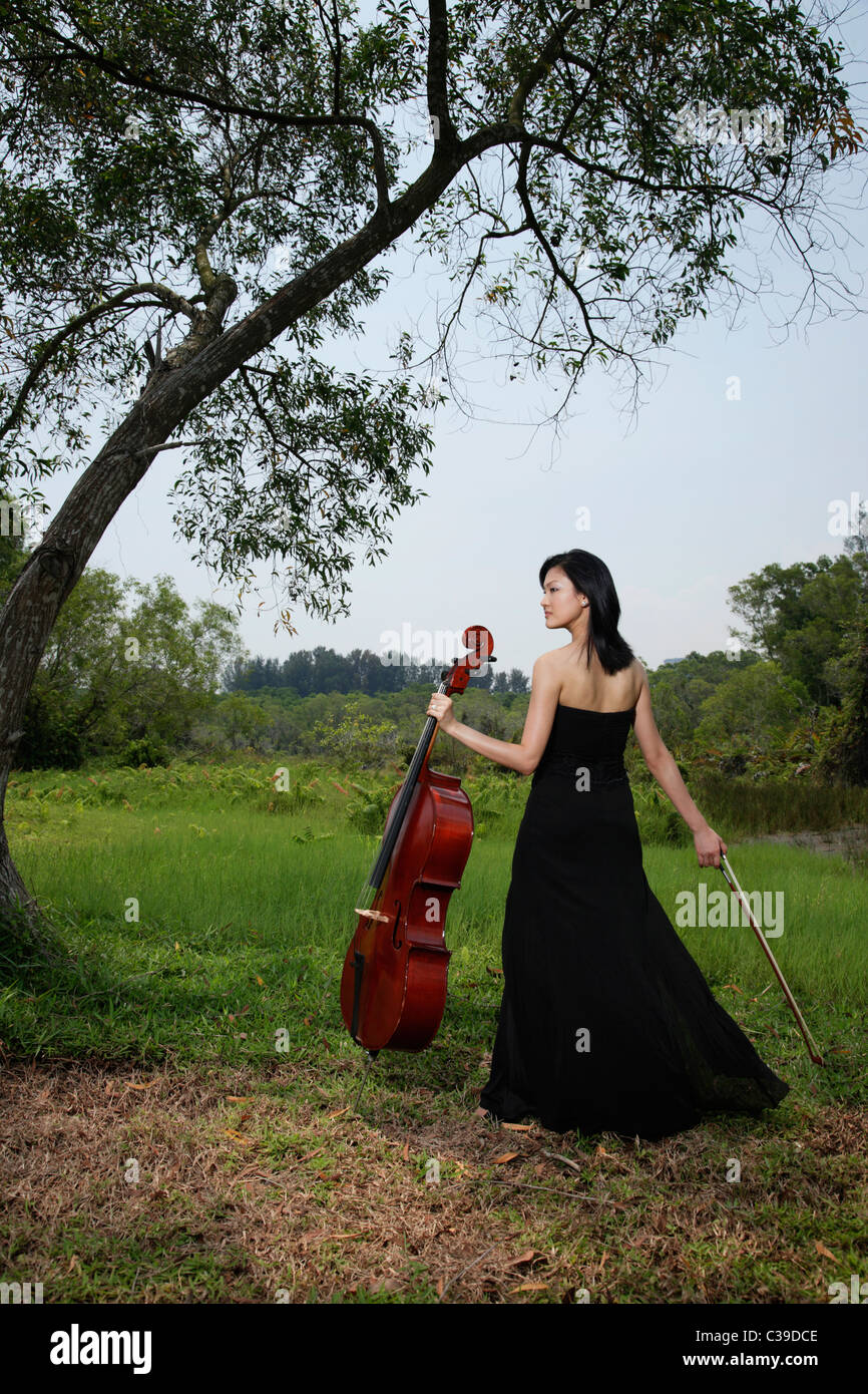 Woman holding cello outside under a tree Stock Photo - Alamy