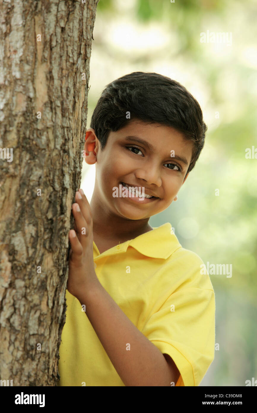 Young boy peeking out from behind a tree Stock Photo - Alamy