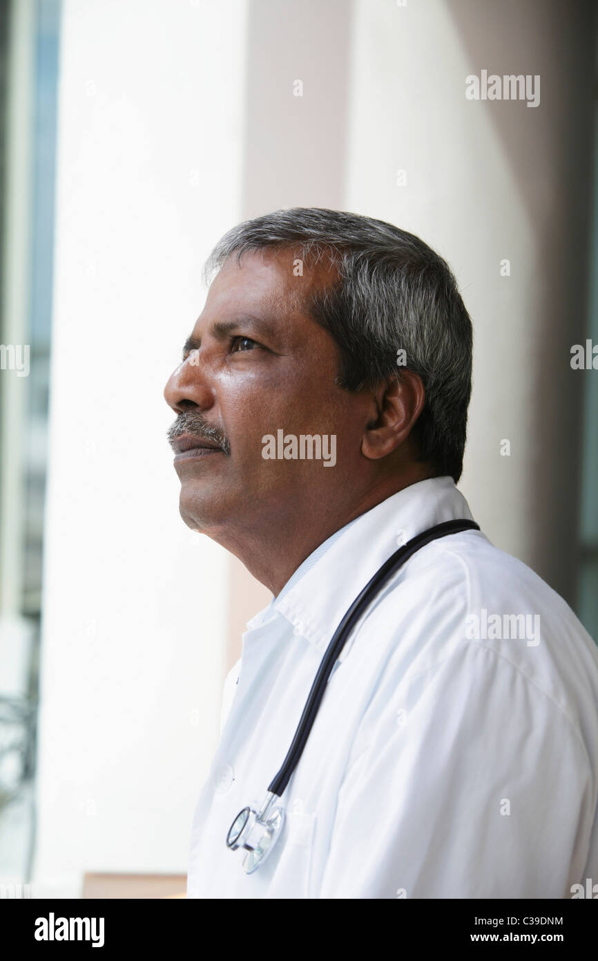 Head shot of Indian doctor looking up and thinking Stock Photo - Alamy