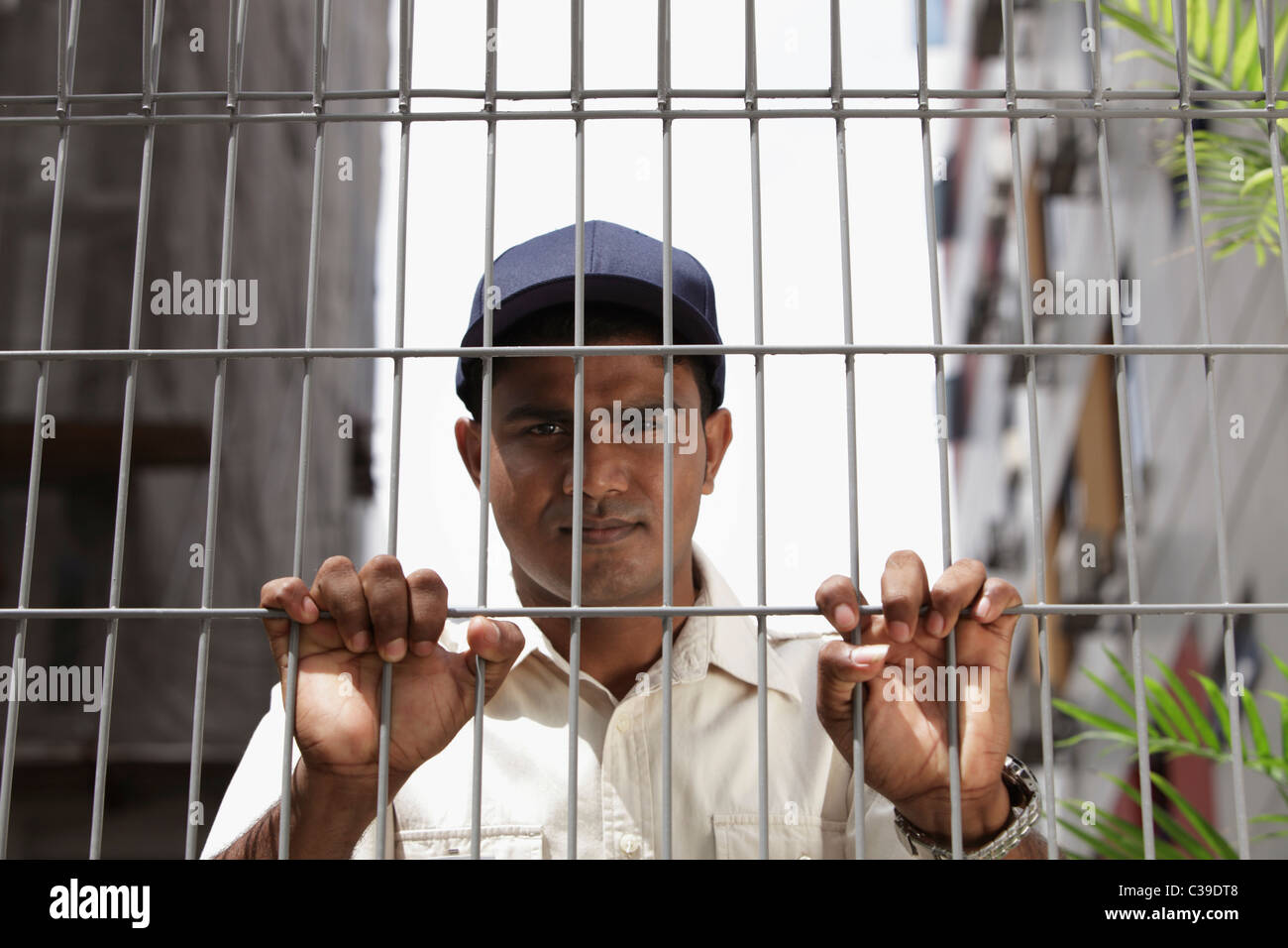 Security guard holding fence and looking stern Stock Photo - Alamy