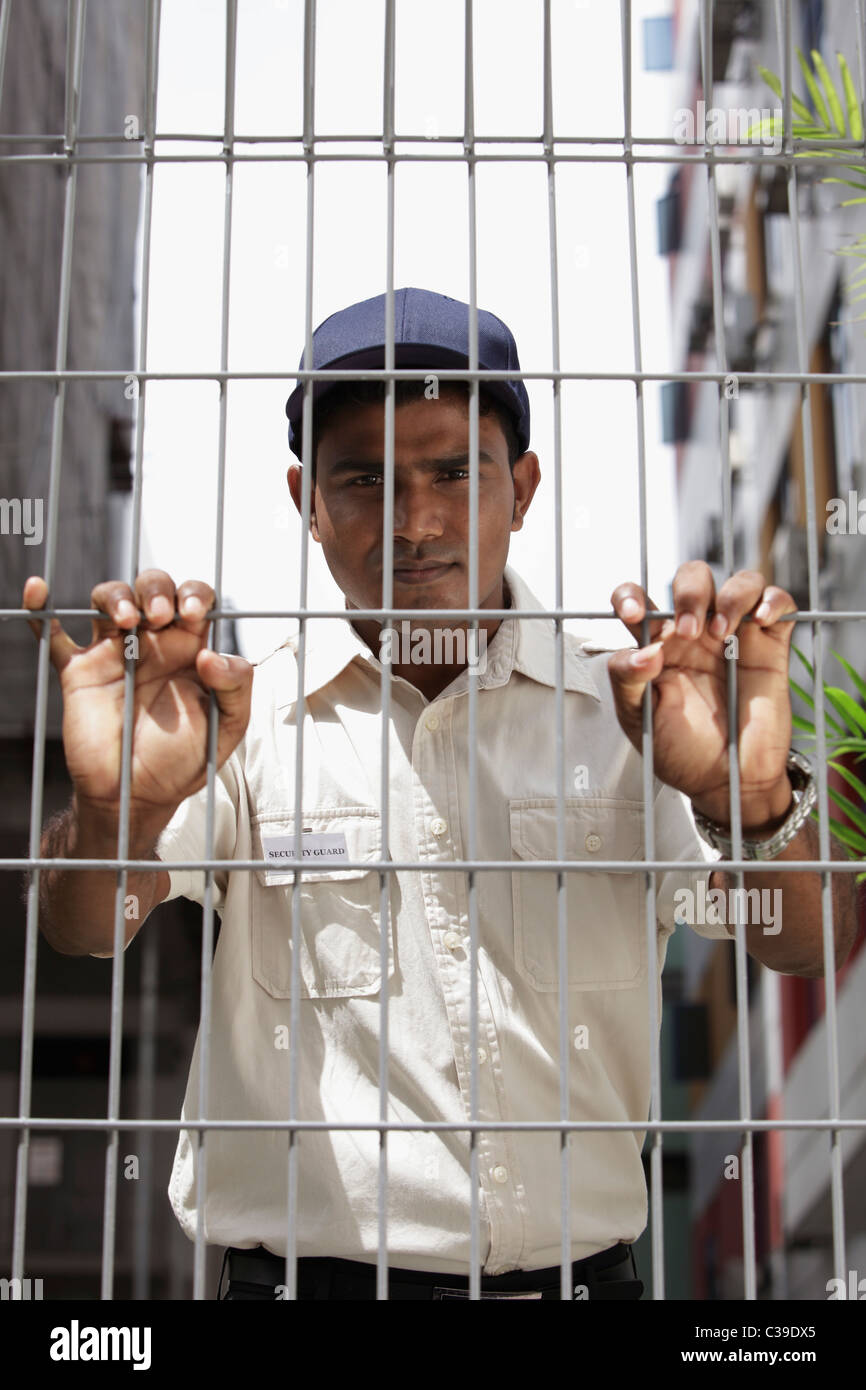 Security guard holding fence and staring Stock Photo - Alamy