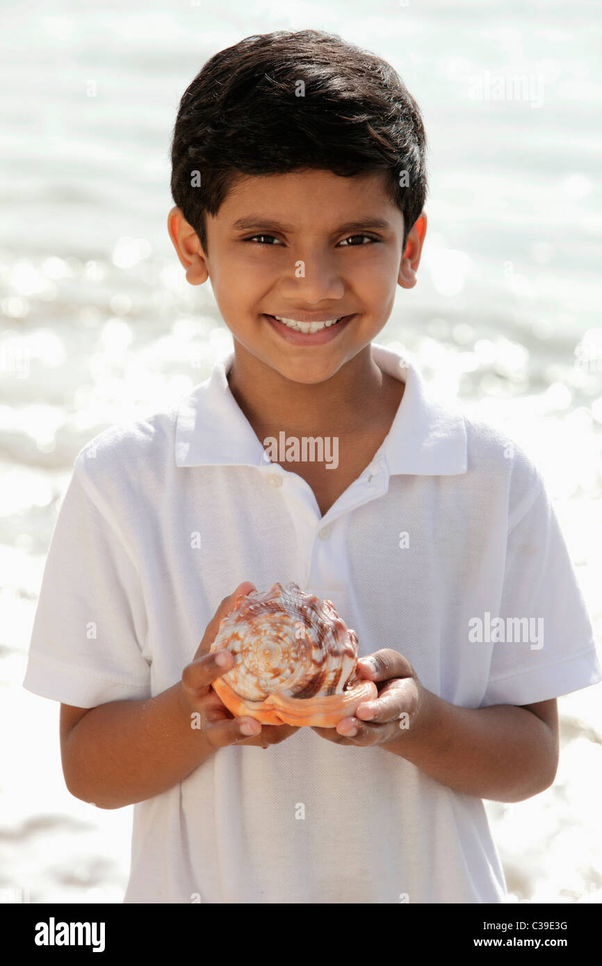 Young boy holding sea shell and smiling Stock Photo - Alamy