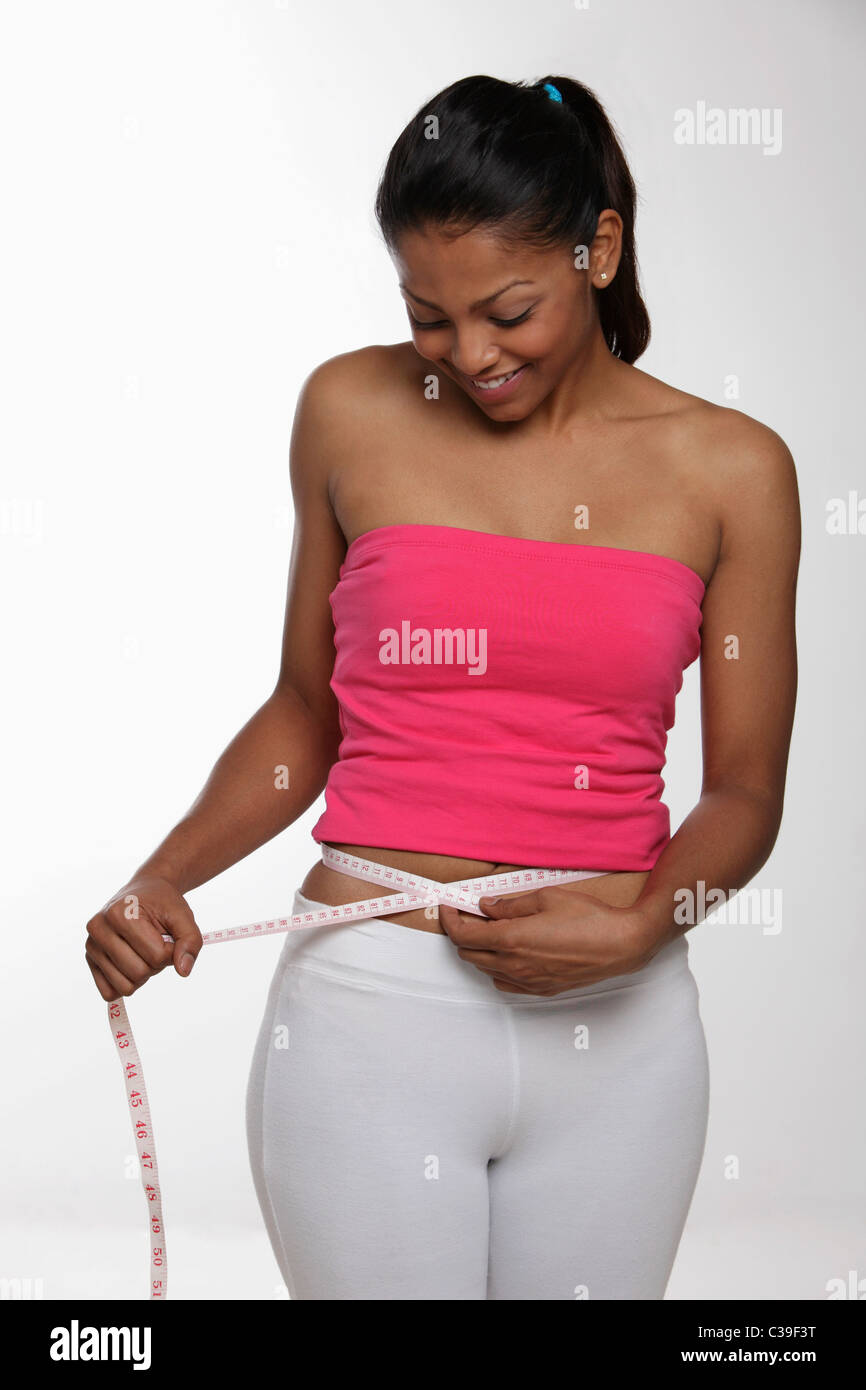 Young woman measuring herself with tape measure and smiling Stock Photo ...
