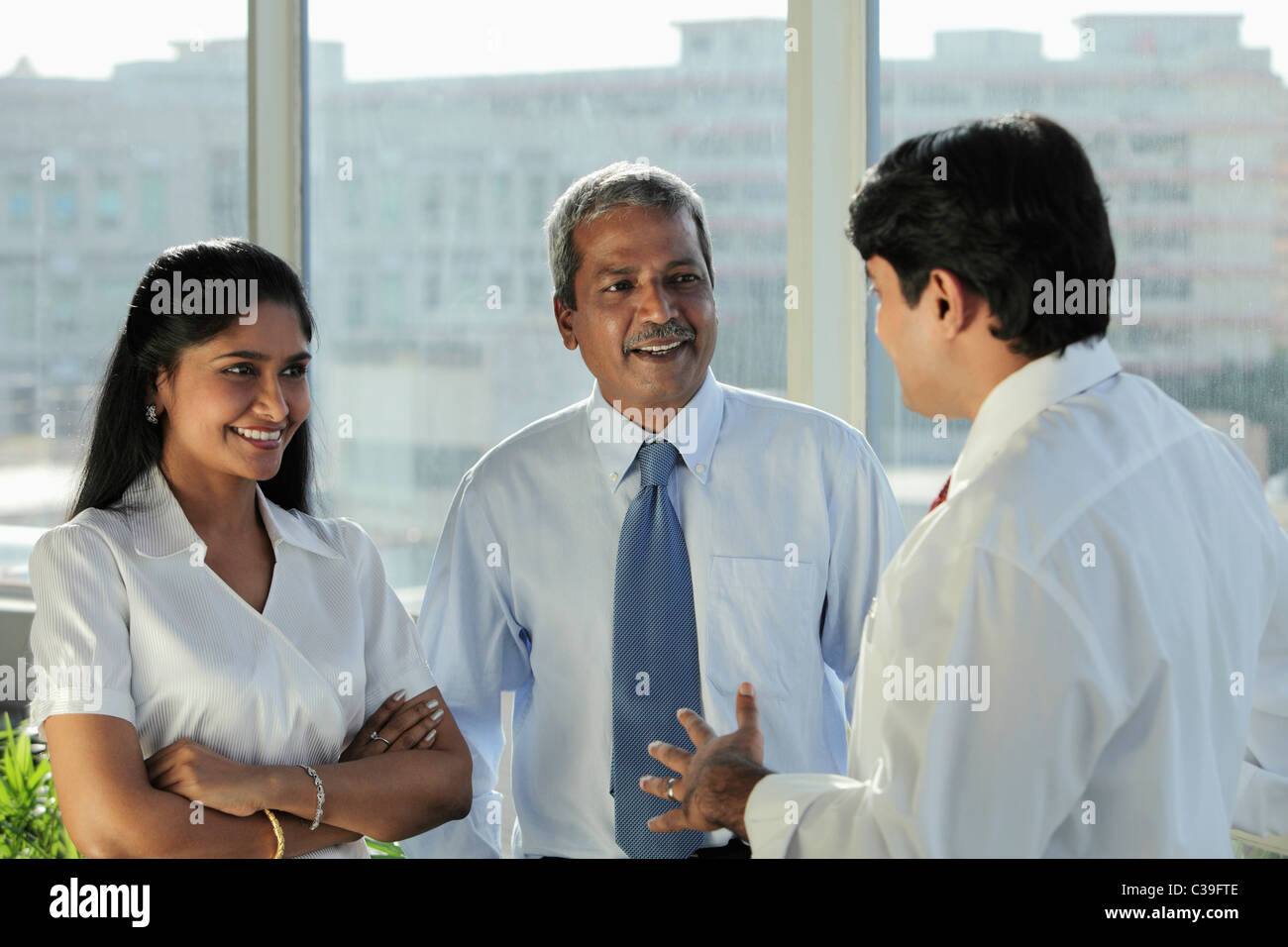 Three Indian people talking together and laughing Stock Photo - Alamy