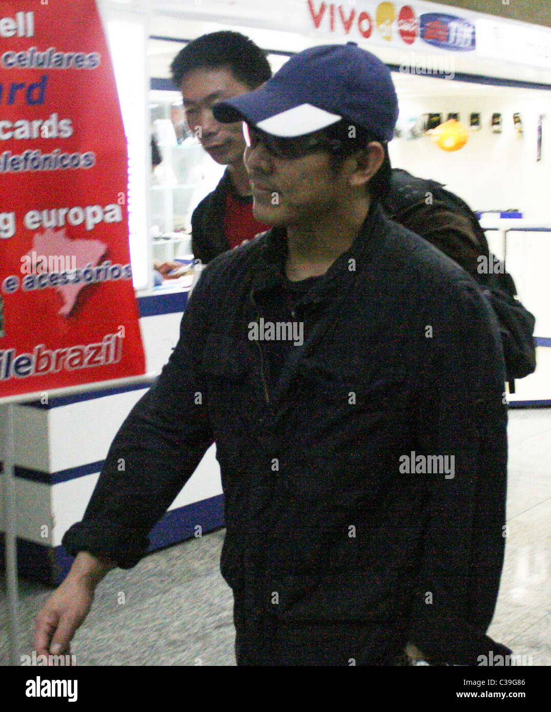 Jet Li tries to hide his face under a hat and sunglasses as he arrives ...