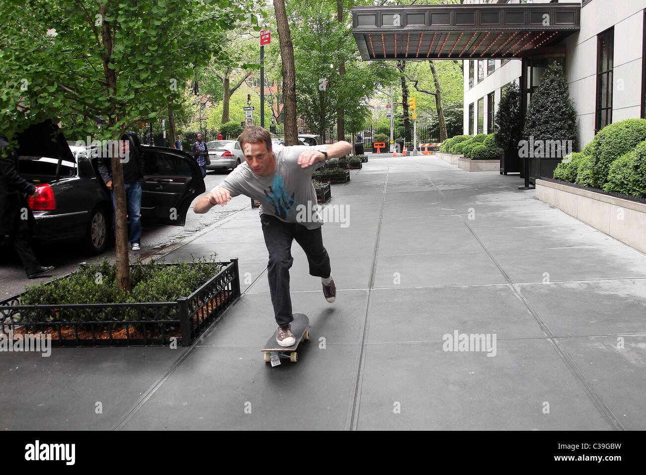 Tony Hawk skateboards for photographers outside his hotel before ...