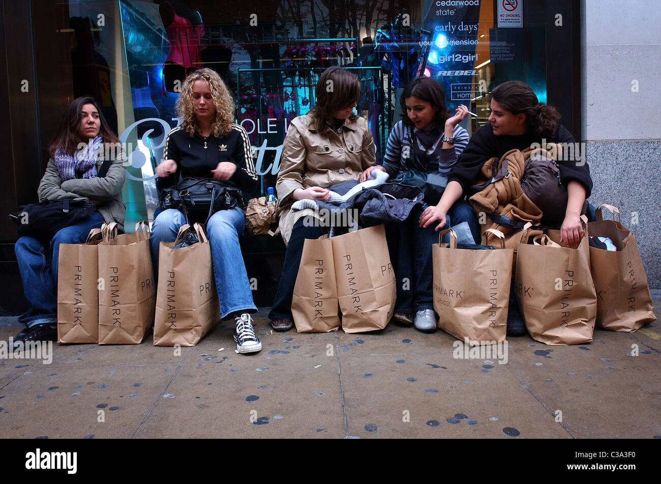 Primark customers relaxing outside the flagship store on Oxford Street ...