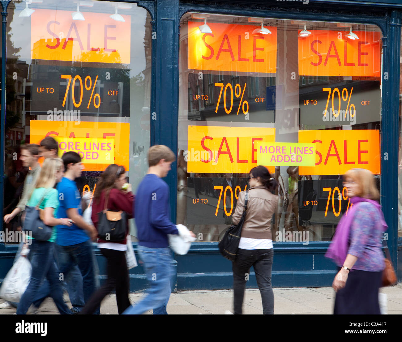 People pass in front of a sale advertisement Stock Photo - Alamy