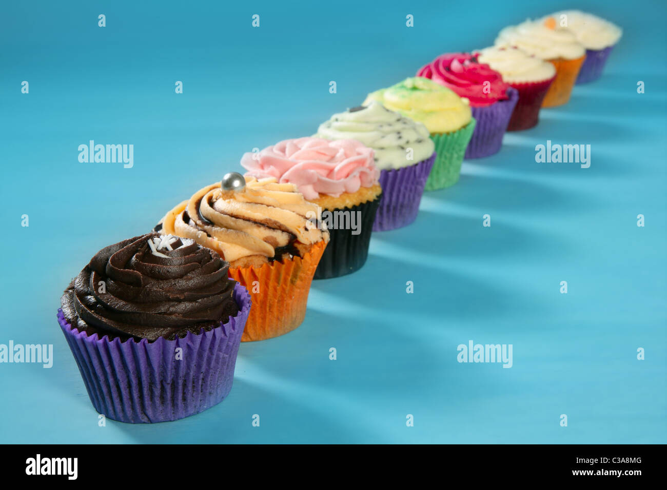 Cupcakes colorful cream muffin arrangement in a row line on turquoise ...