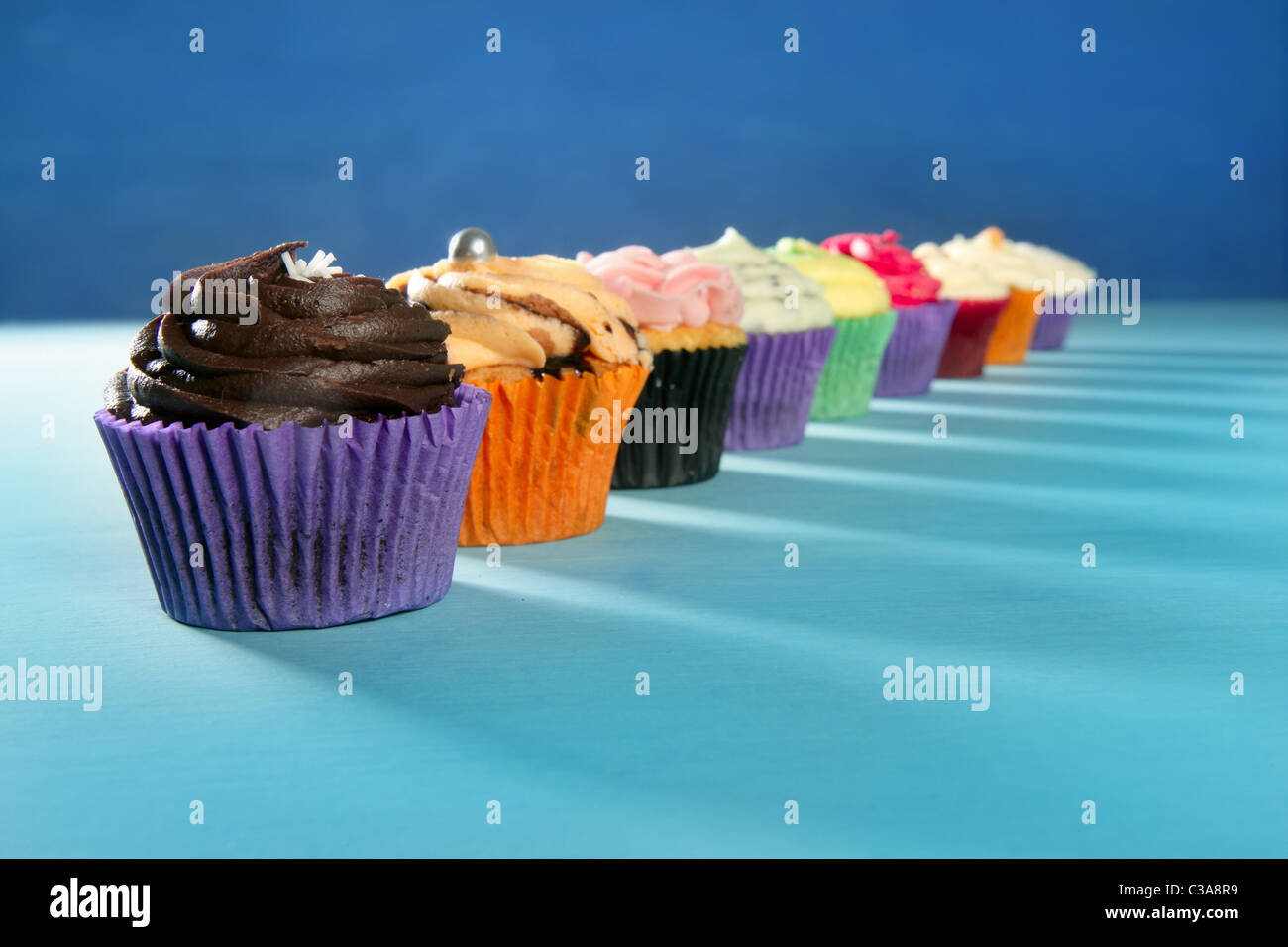 Cupcakes colorful cream muffin arrangement in a row line on turquoise ...