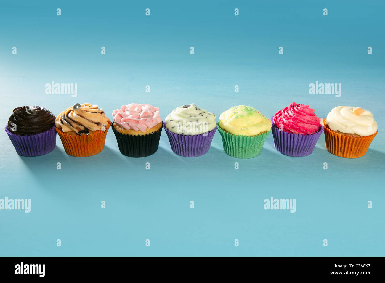 Cupcakes colorful cream muffin arrangement in a row line on turquoise ...