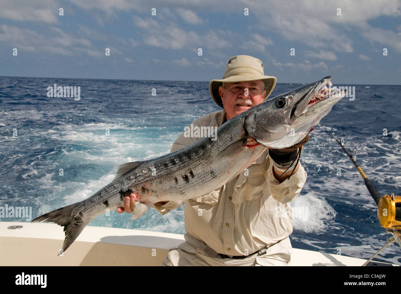 An angler lifts his nice catch, a big barracuda, caught off the beach ...