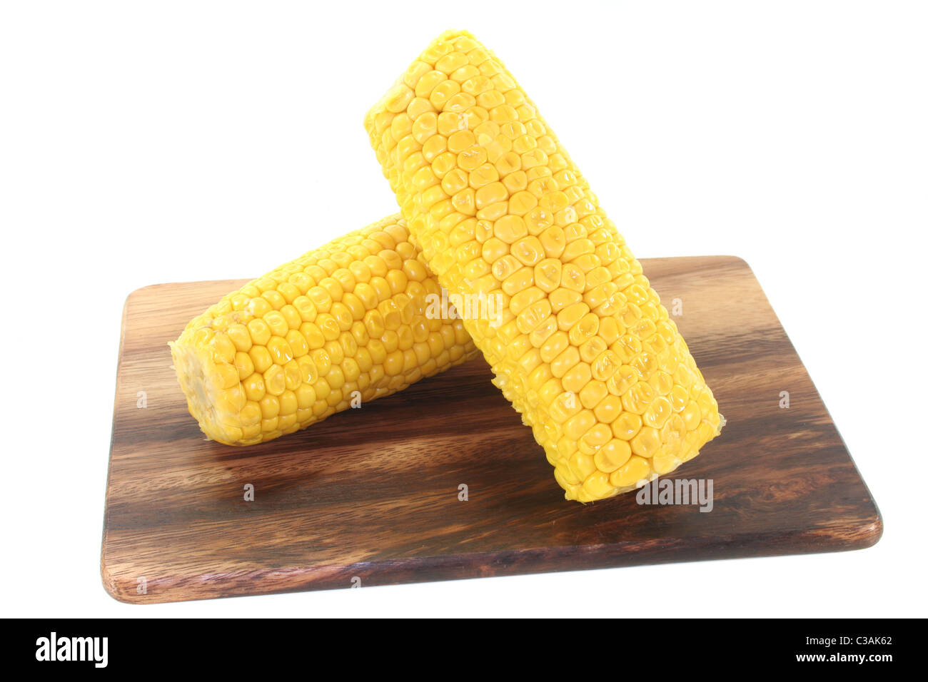 two corn on a wooden board before white background Stock Photo - Alamy