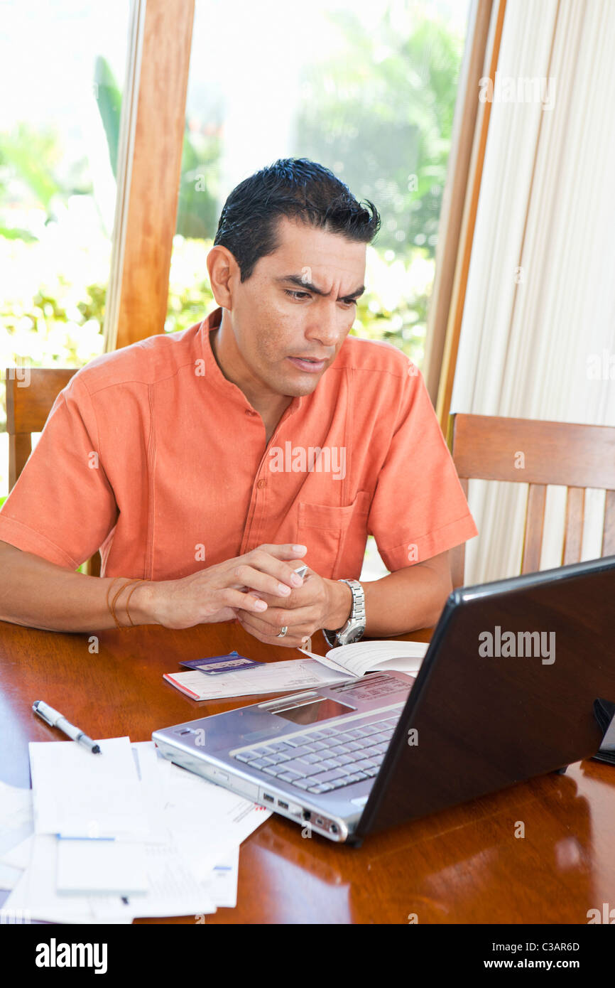 man at table with bills and laptop Stock Photo - Alamy