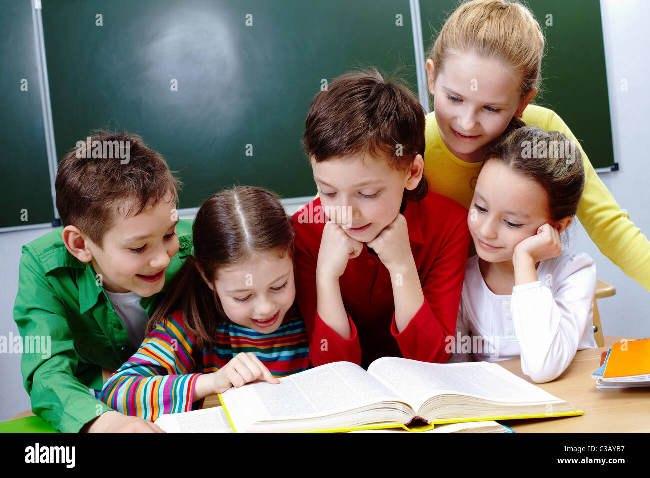Portrait of friendly group reading book in classroom Stock Photo - Alamy