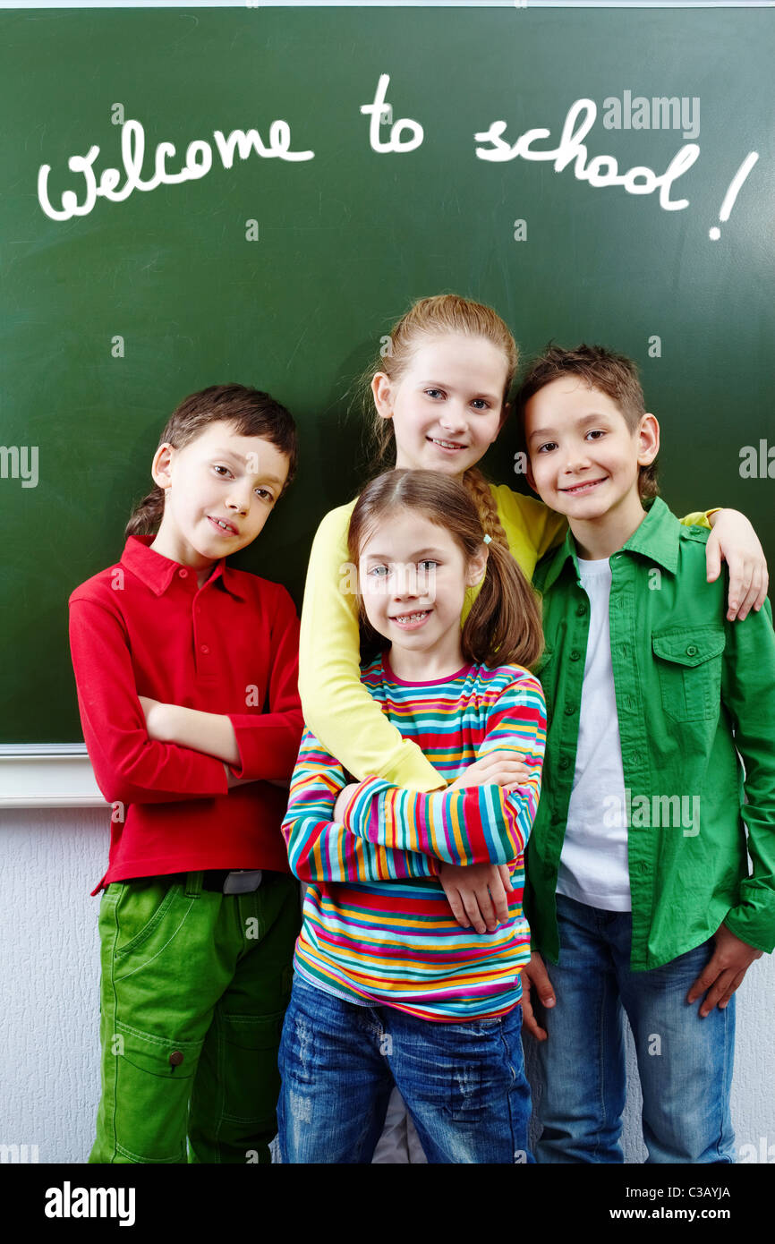 Group of happy classmates together by whiteboard with text welcome to ...