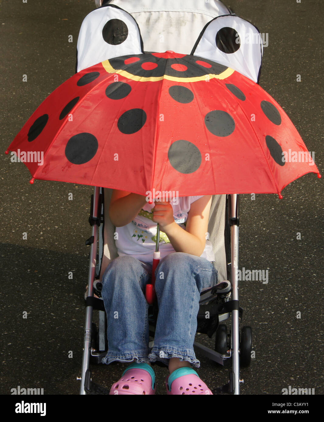 Child under a lady bug umbrella Stock Photo - Alamy