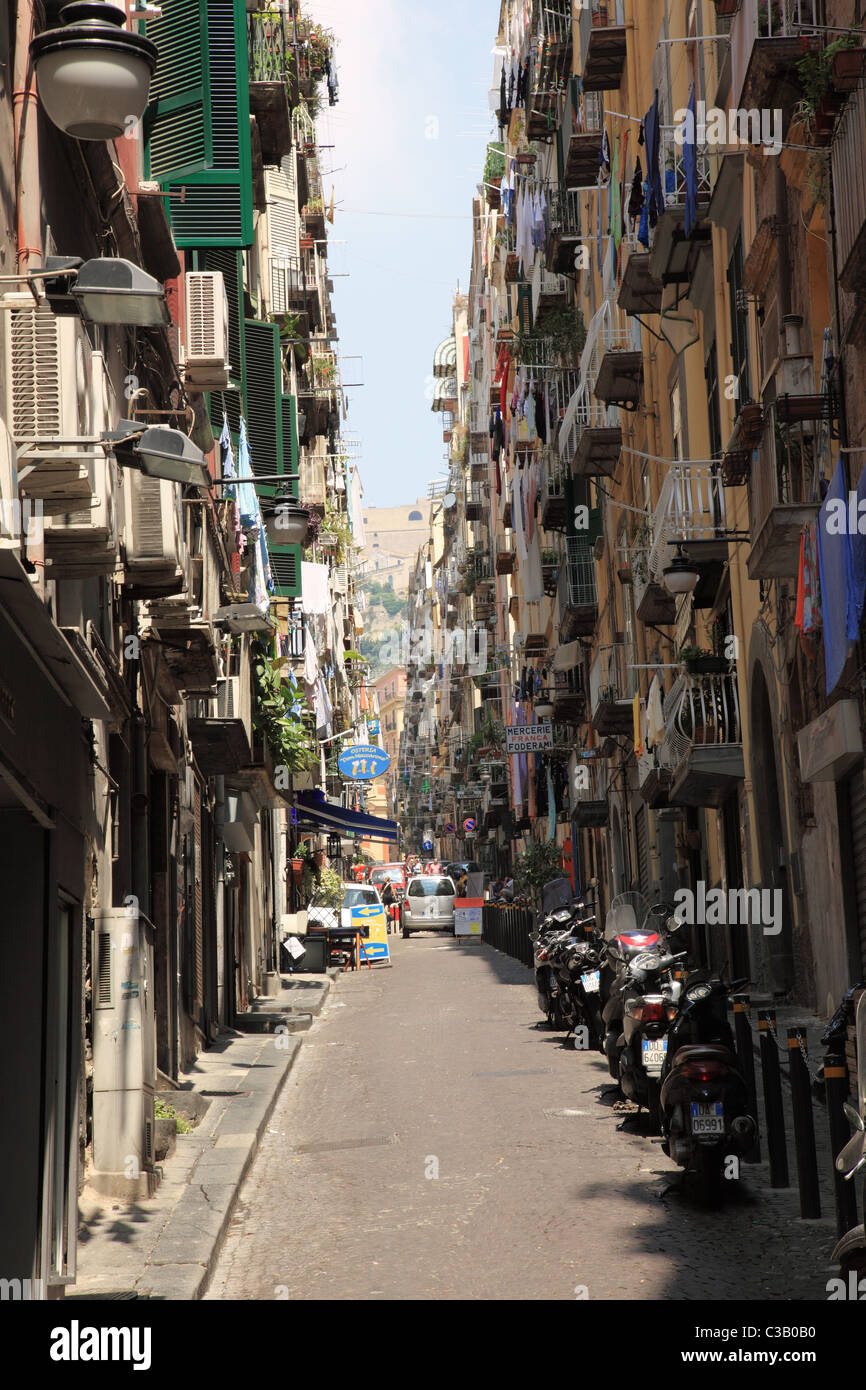 A narrow street in Naples with hanging washing and scooters filling the ...