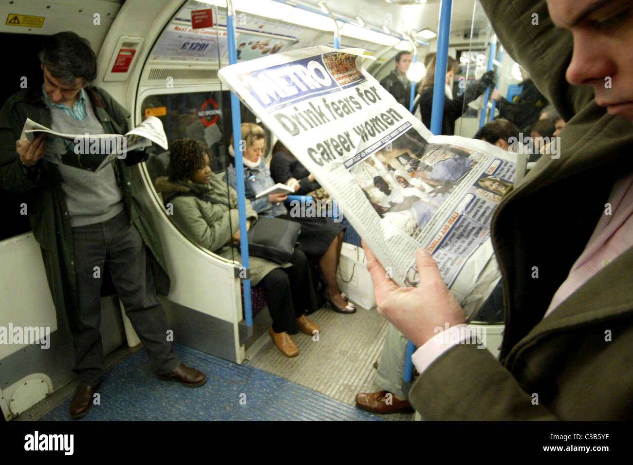A man reading the MTERO newspaper on a Victoria line underground train ...