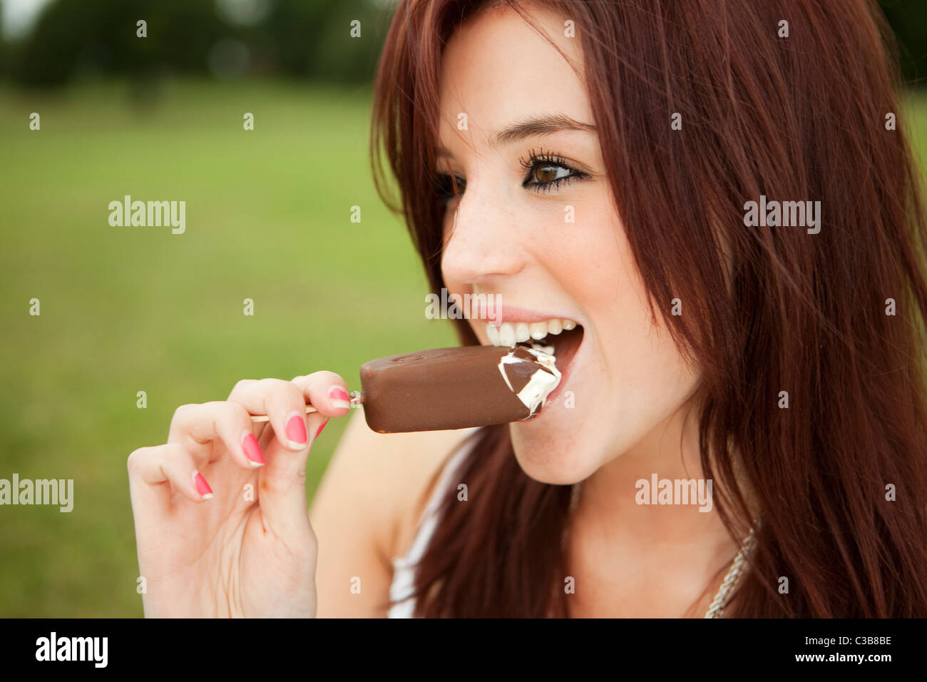 A girl relaxing in the park, enjoying a Magnum ice-cream Stock Photo ...