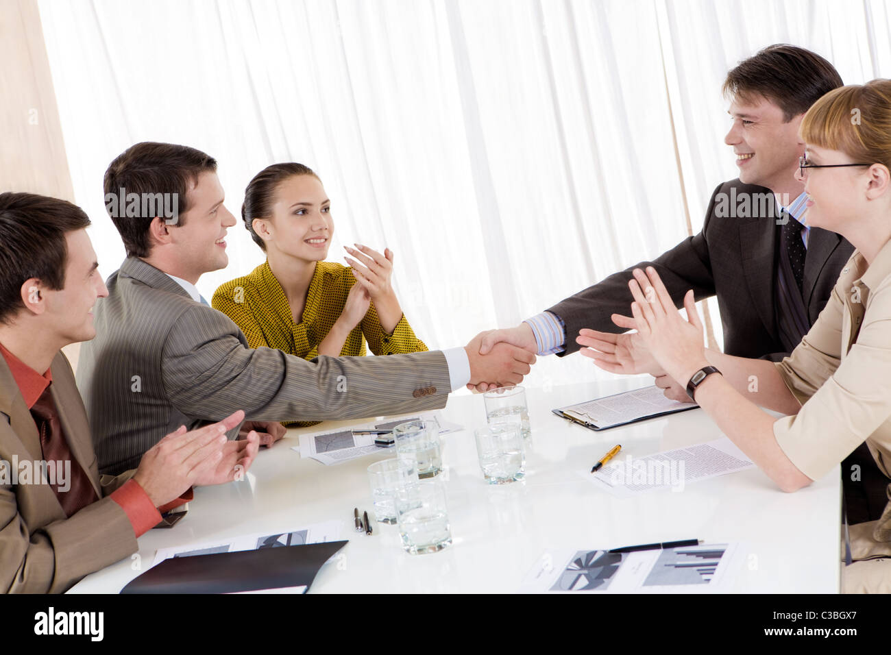 Photo of successful business partners handshaking after striking great deal with applauding ...