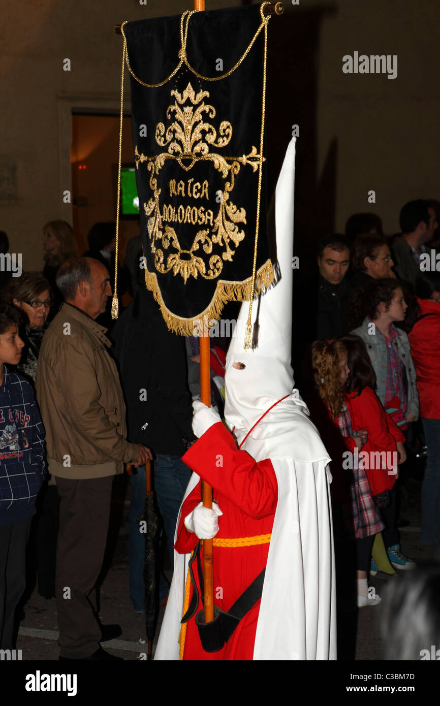 A penitent (Narareno) in a pointed hood (capirote) carries a banner ...