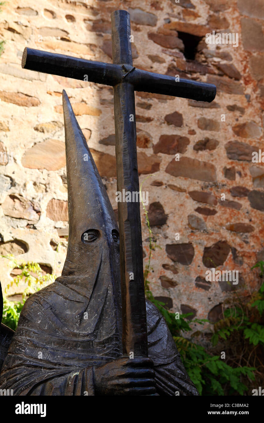 Statue of a penitent (Nazareno) in a pointed hood (capirote) carrying a ...