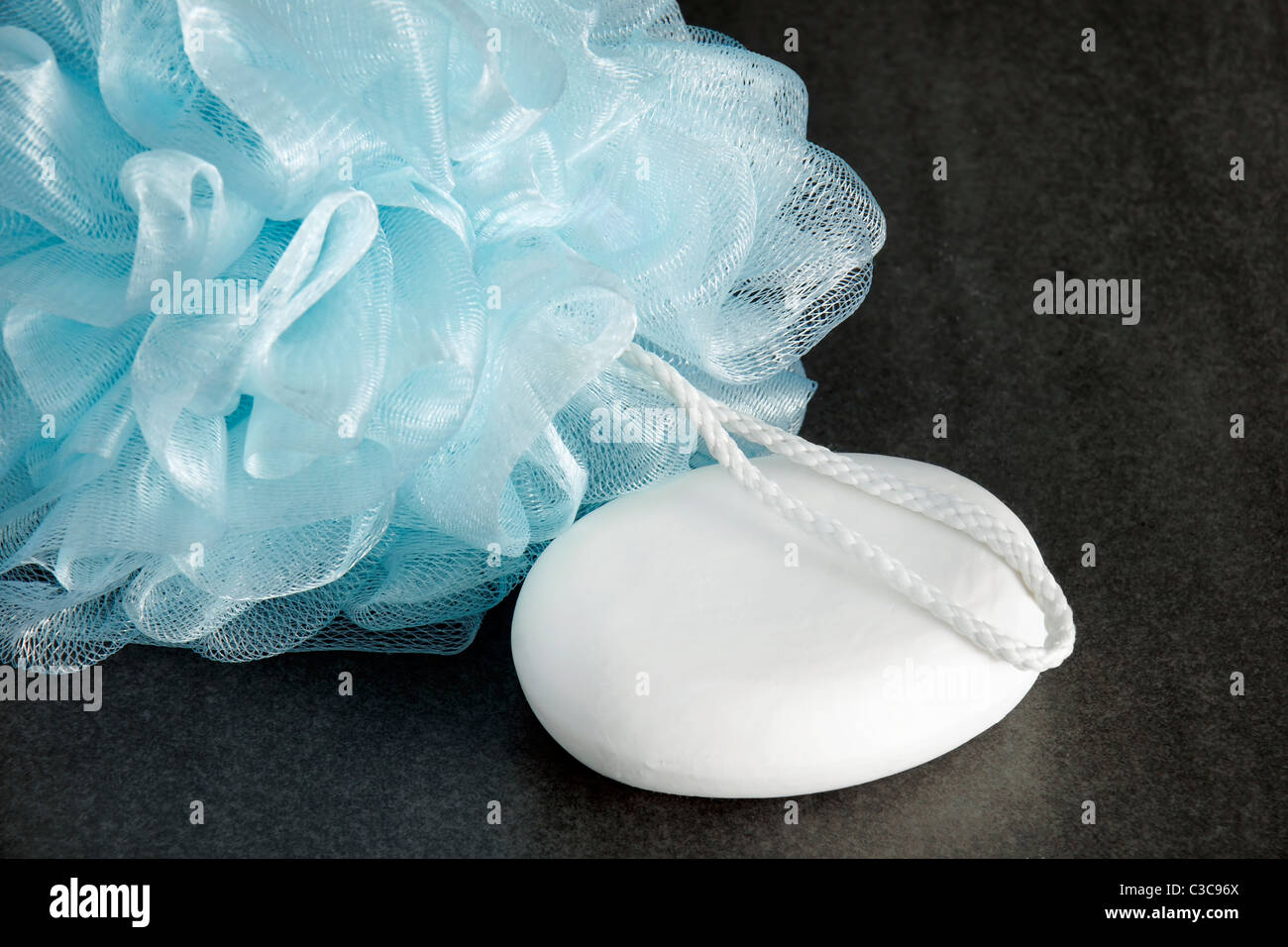 At the spa: light blue shower puff with bar of soap on dark stone tile ...