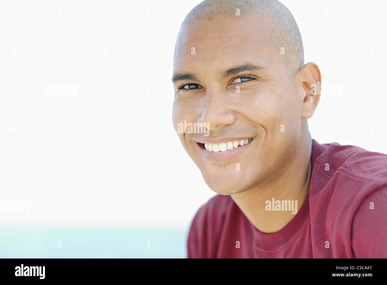 portrait of young hispanic guy with shaved head looking at camera near ...