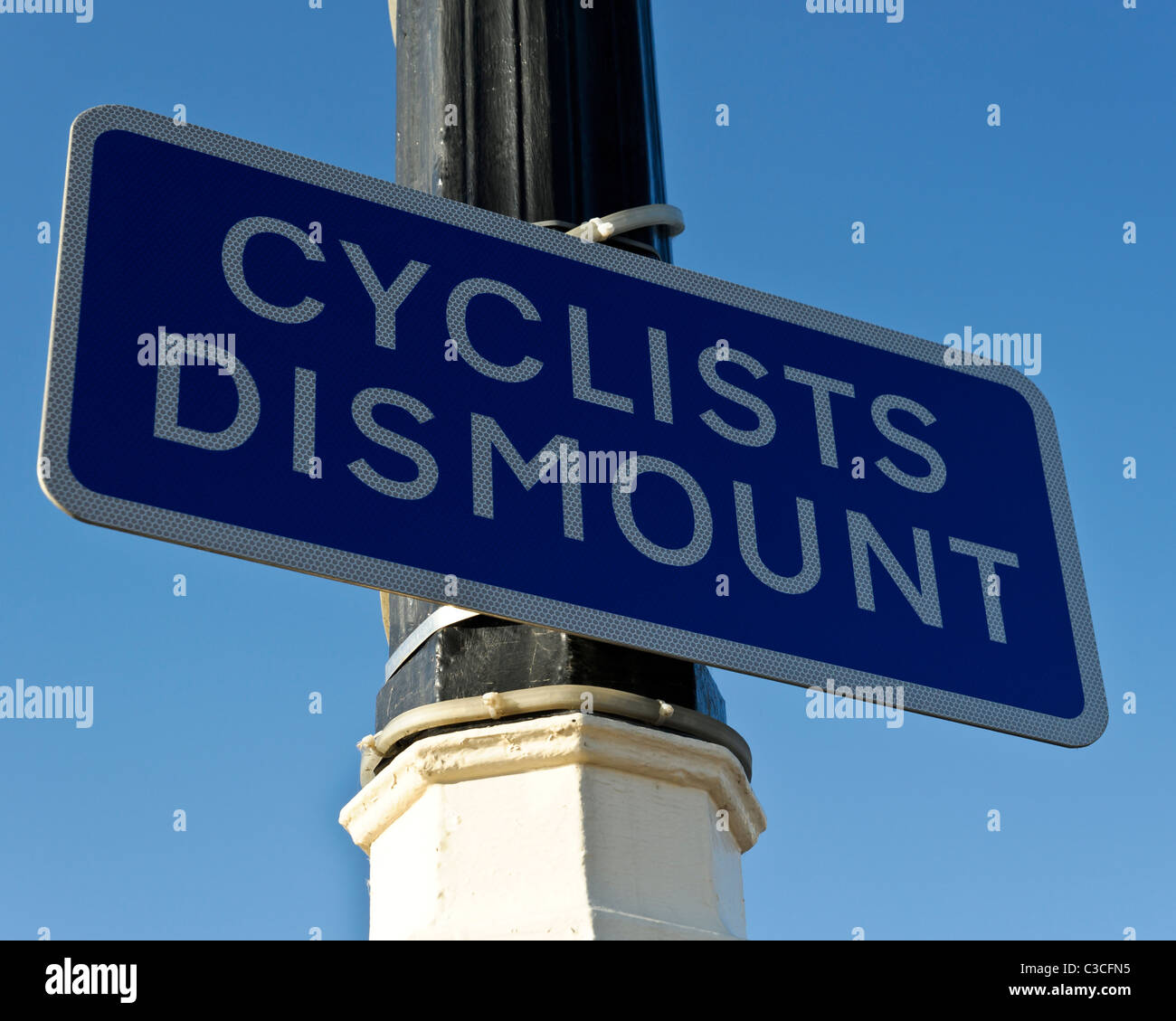 Cyclists Dismount sign mounted on a lamppost with a clear blue sky ...