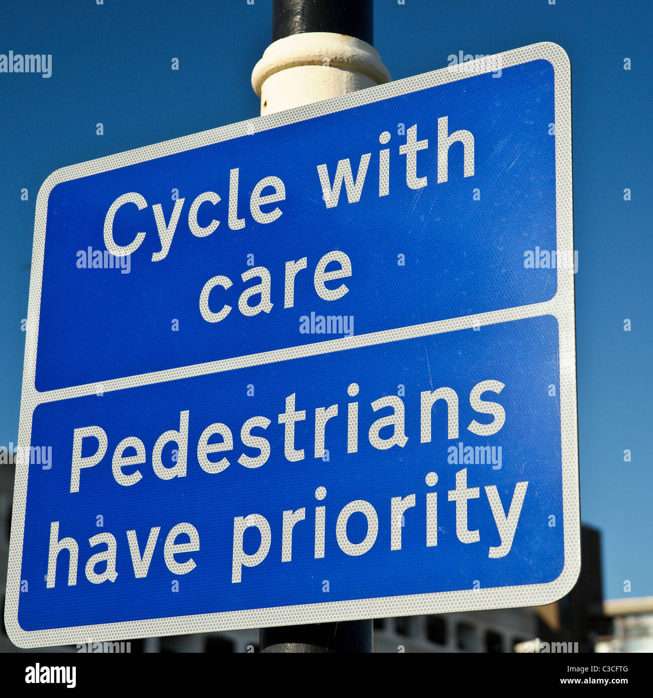 Cycle with Care sign mounted on a lamppost with a clear blue sky behind ...