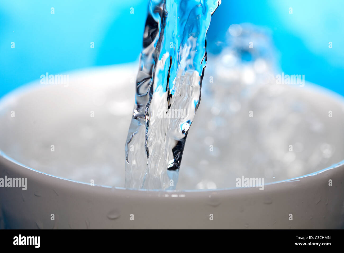 water splash in a cup on a blue background Stock Photo - Alamy