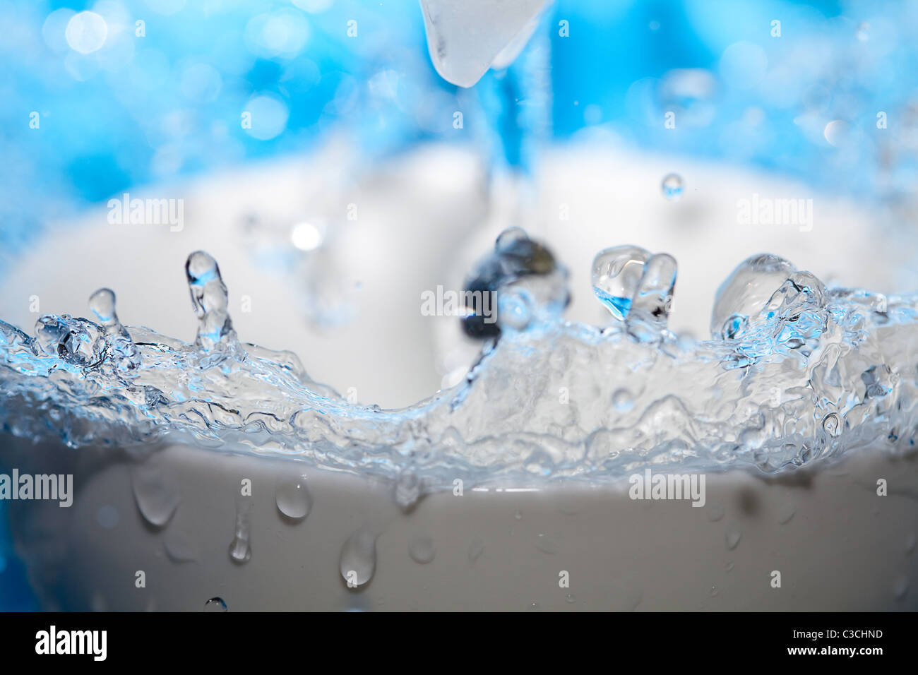 water splash in a cup on a blue background Stock Photo - Alamy