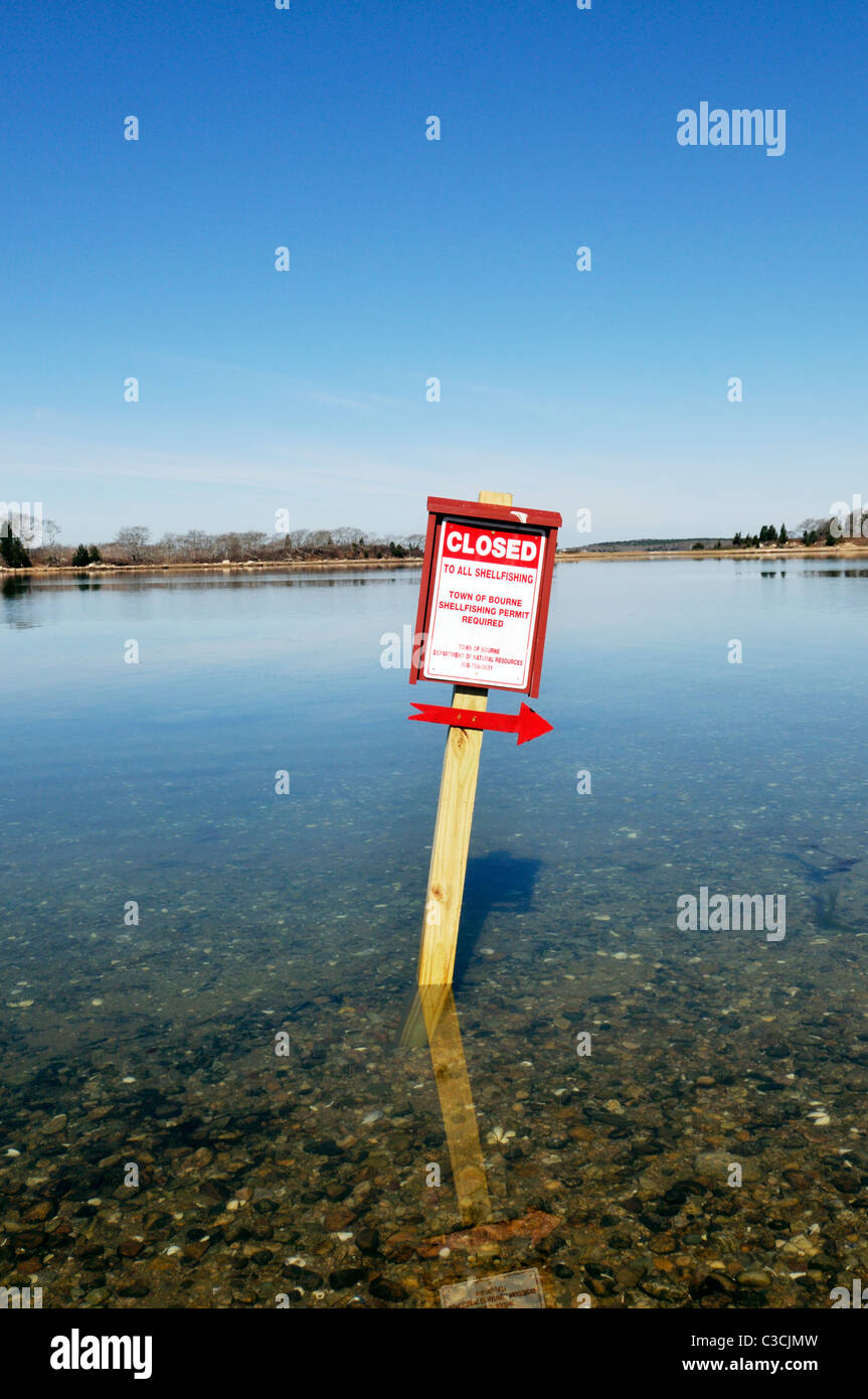 Closed to all shellfishing sign with red area posted in shallow water ...