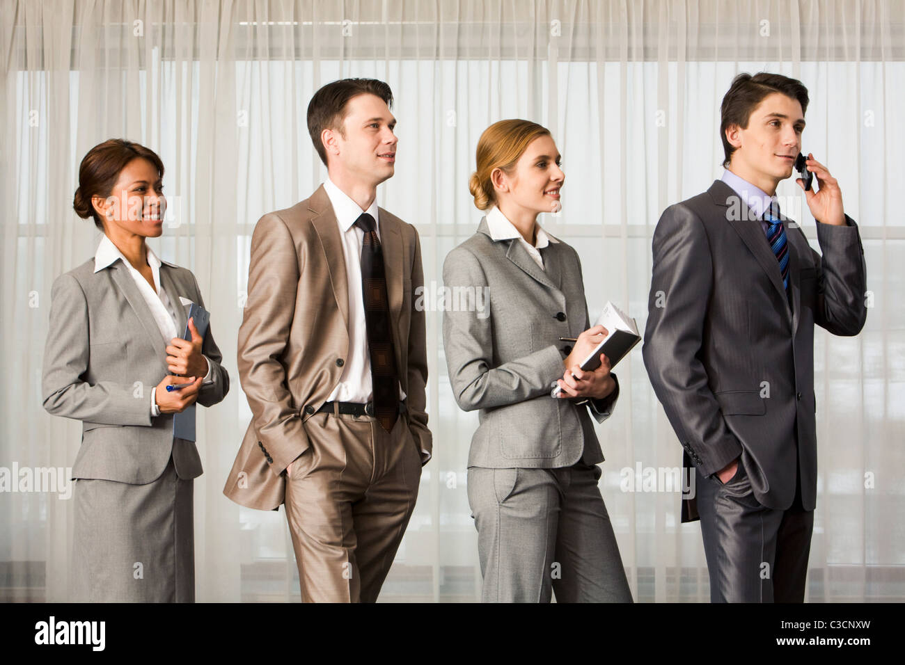 Contemporary business people standing in line and looking aside with ...