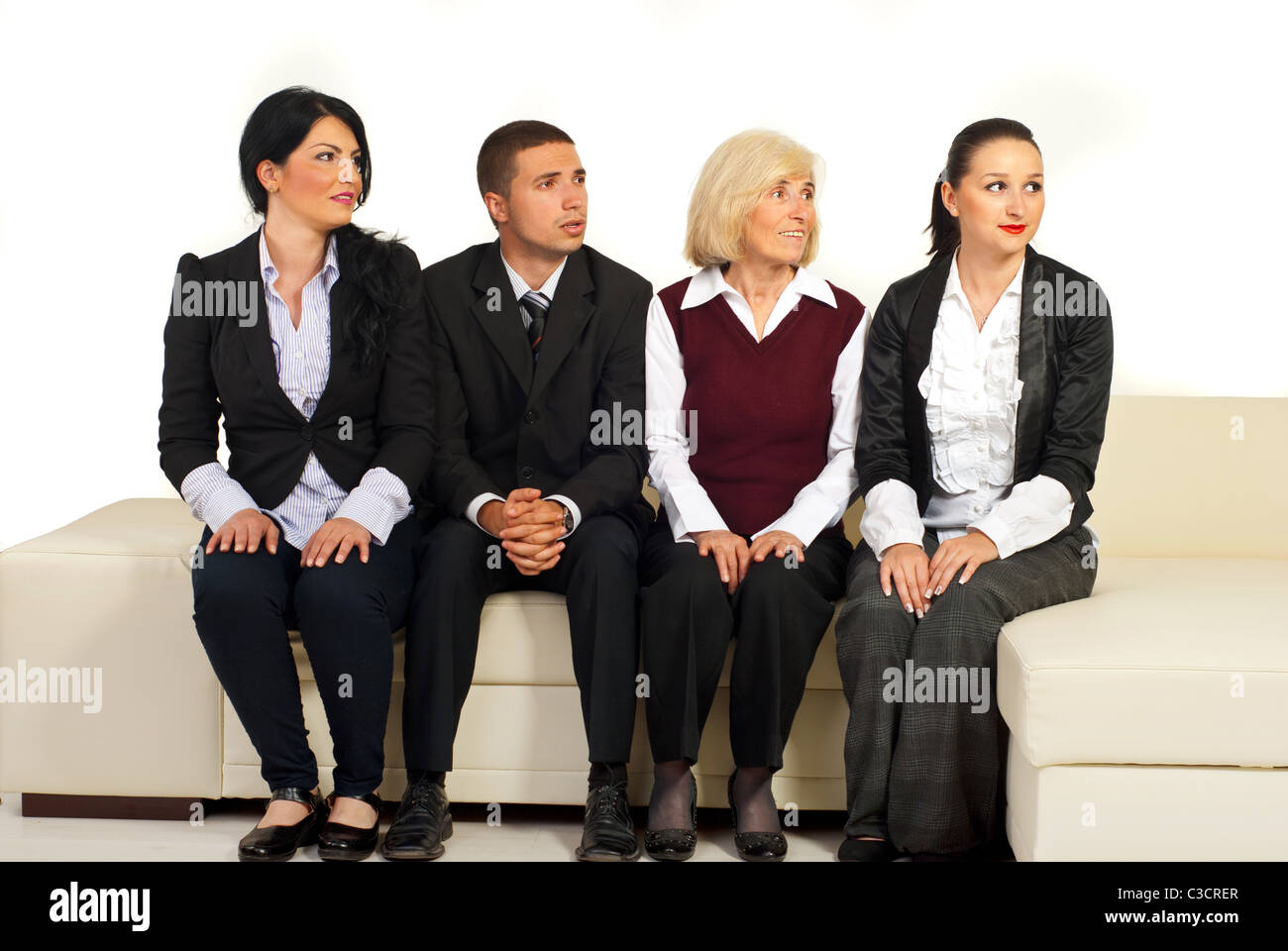 Four business people sitting in a row on sofa and looking in right part ...