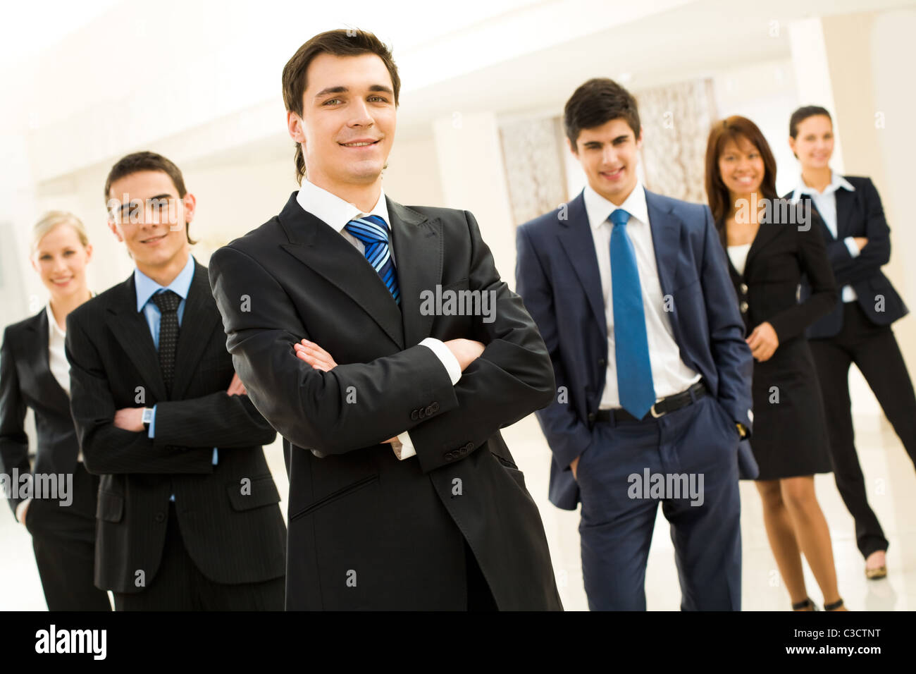 Smart businessman looking at camera at background of his friendly ...