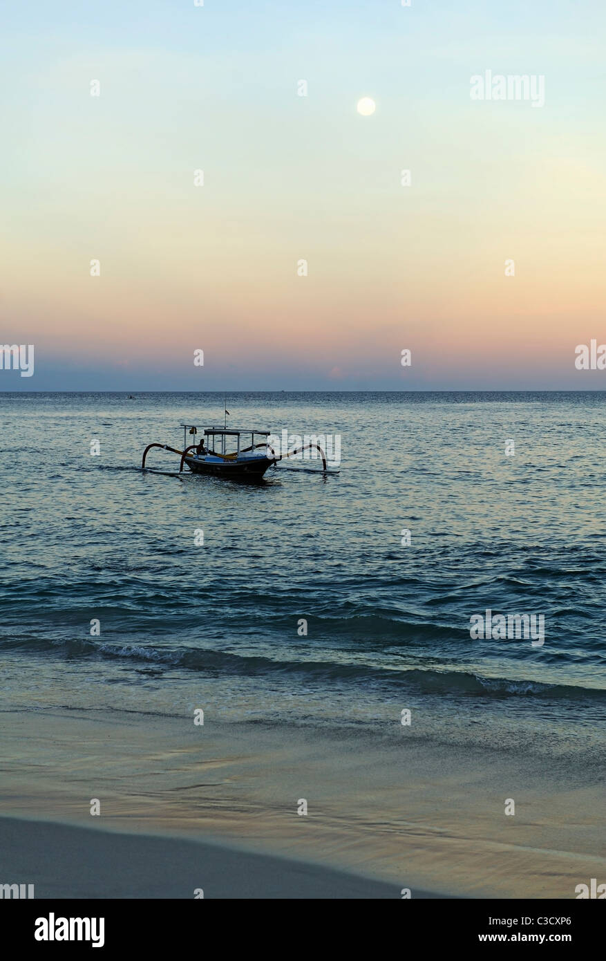 a traditional jukung boat in the sea of the coast of bali, indonesia at ...