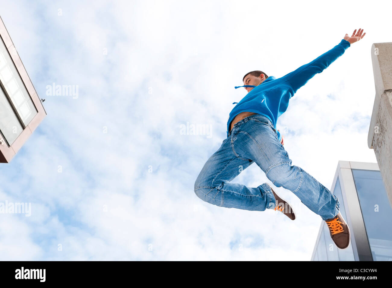 Jumping young man in front of buildings Stock Photo - Alamy